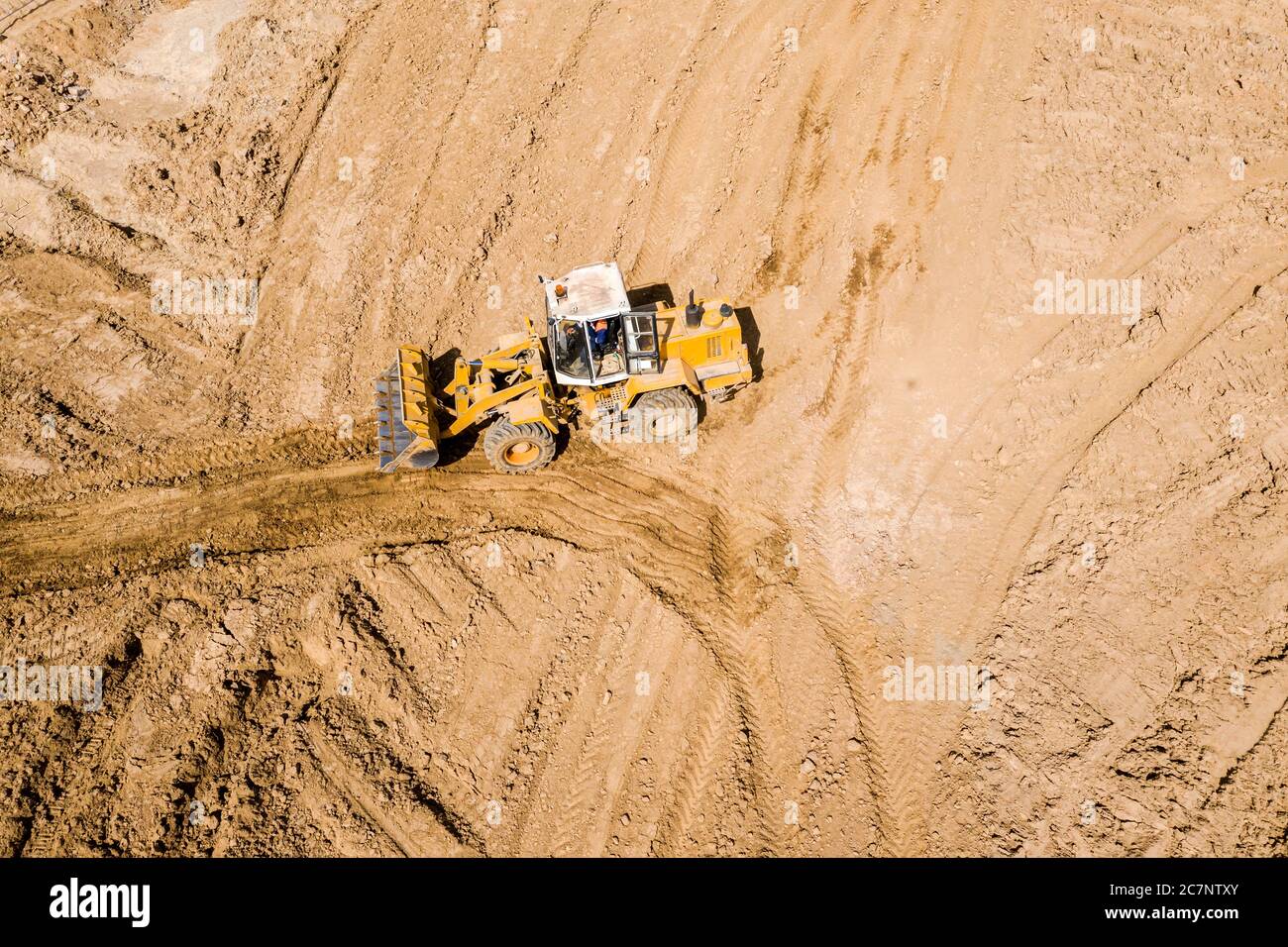 yellow wheel loader working in construction site, grading the land ...