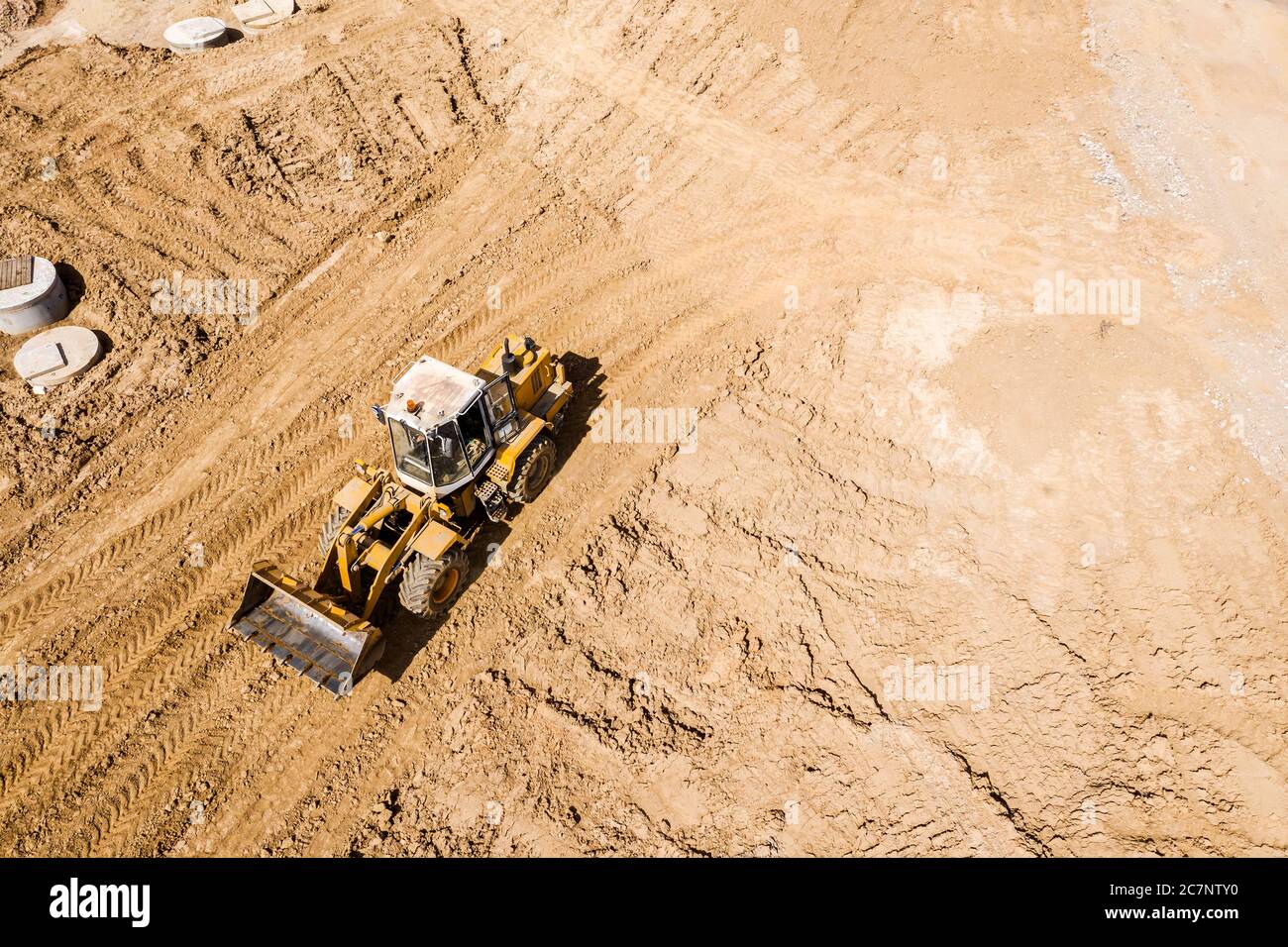 yellow wheel loader doing earthmoving work at construction site ...