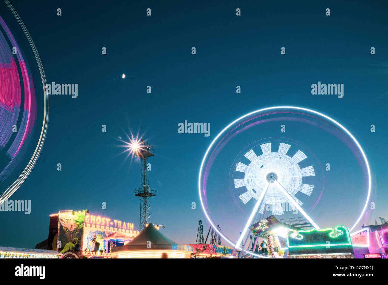 Ferris wheel at amusement park moving at night doing lightpainting ...