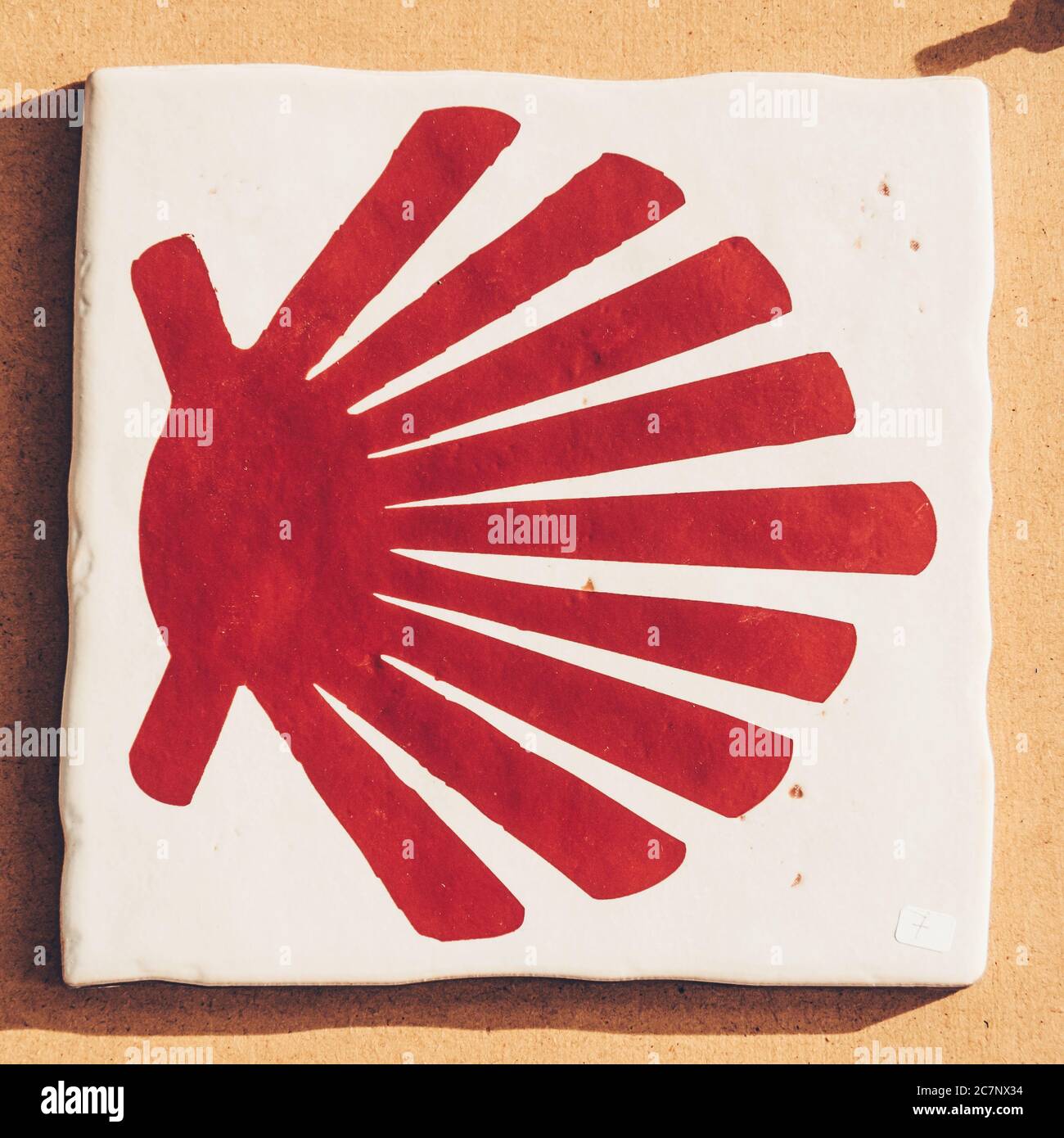 Overhead shot of a painted red scallop shell symbol on a white stone ...