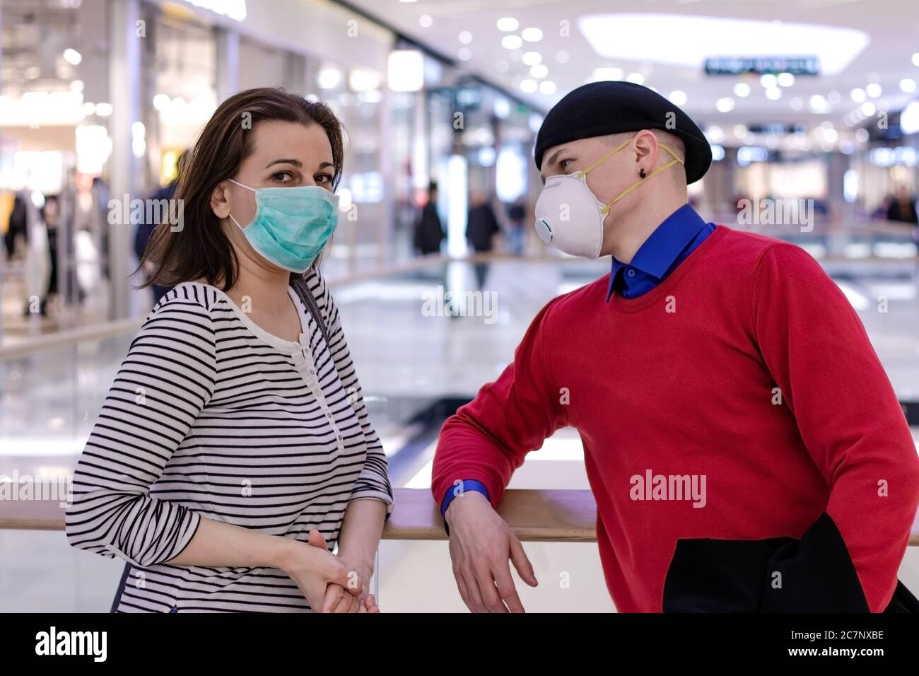 Male and a female wearing surgical masks in a mall to prevent catching ...