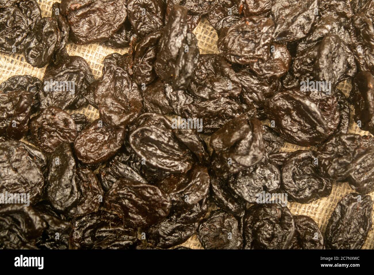 Dried prunes in bulk on burlap with a rough texture. Close up Stock ...