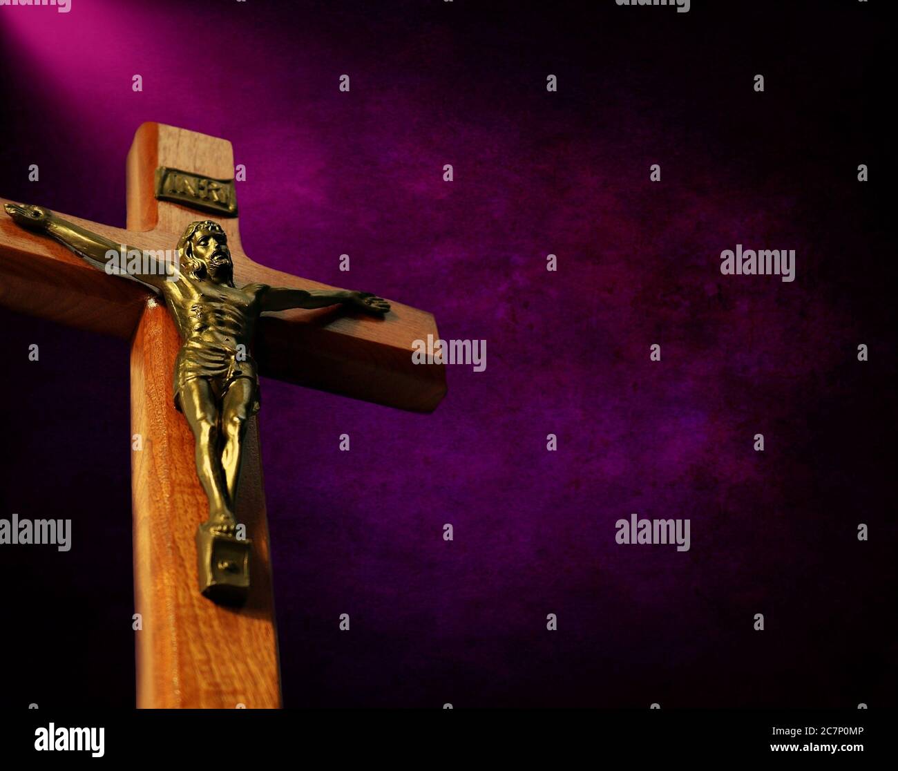 Closeup shot of wood crucifix with gold body of Christ on dark purple ...