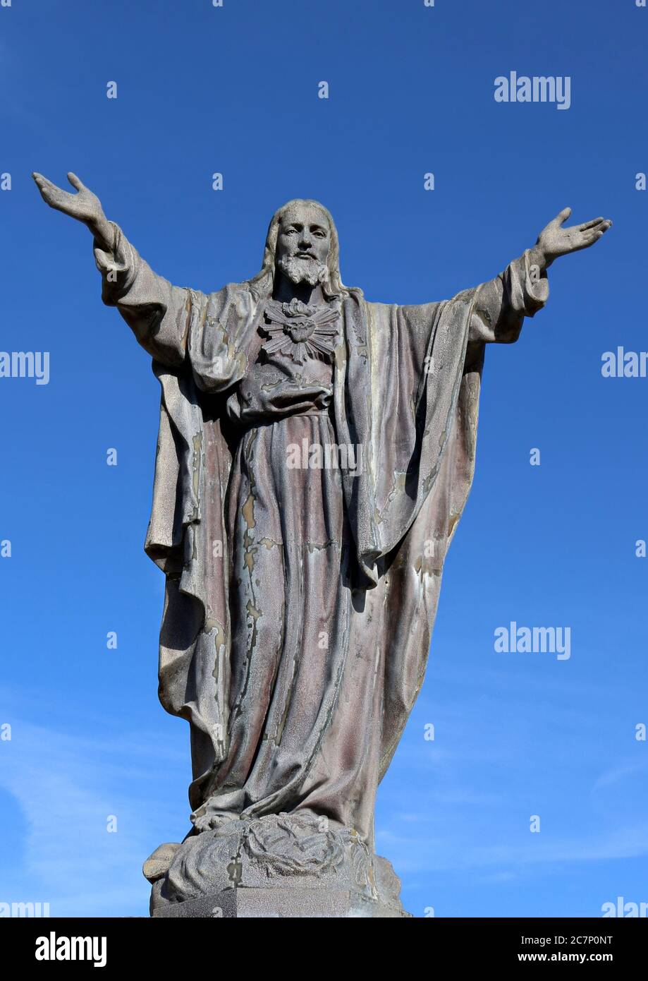 Vertical shot of a concrete statue of Jesus Christ isolated on blue sky ...
