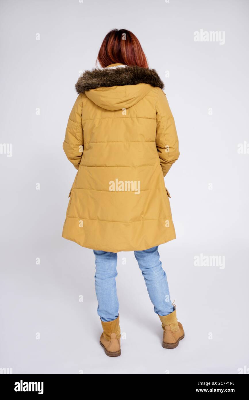 back view of woman in warm winter clothes posing over grey background ...