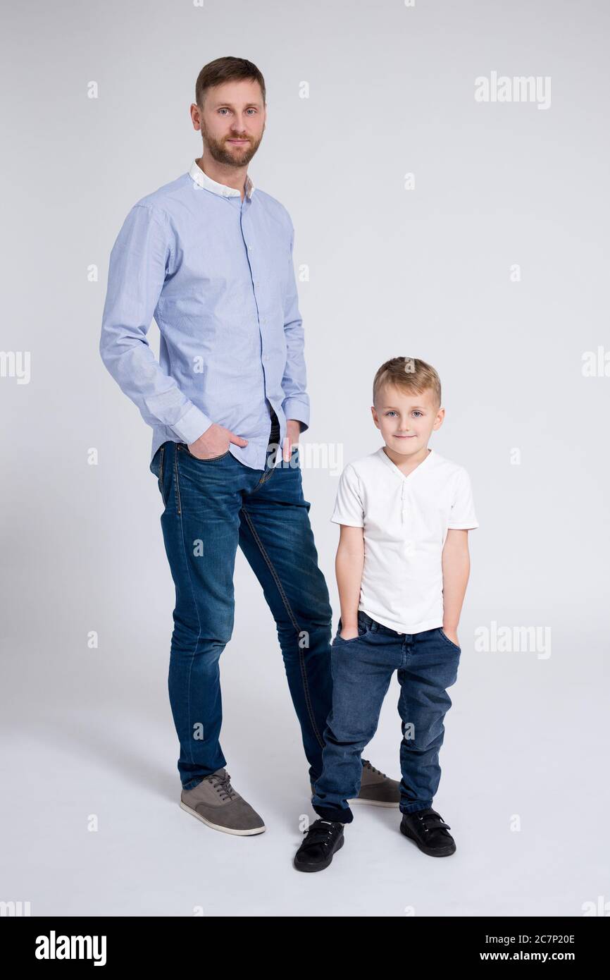 full length portrait of young father and little son posing over white ...