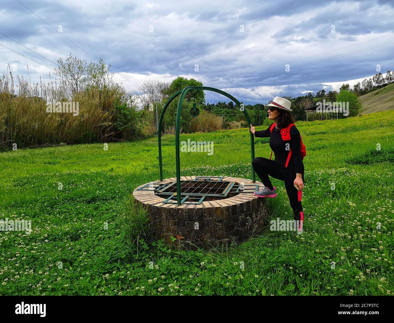 Picture of a female leaning on a closed well in a field Stock Photo - Alamy