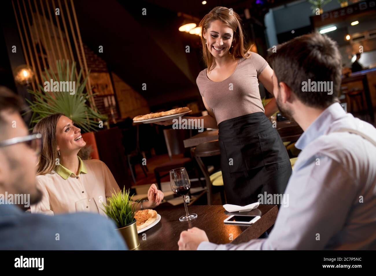 Smiling waitress serving pizza hi-res stock photography and images - Alamy