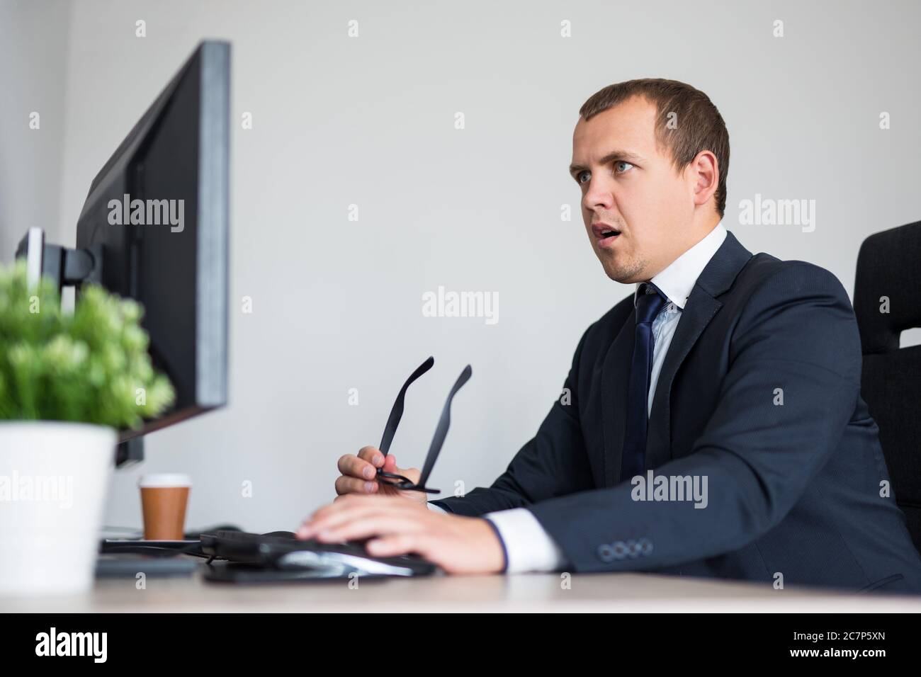 portrait of young surprised or shocked business man using computer in ...