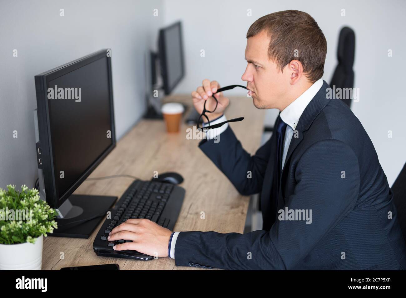 portrait of young thoughtful business man working with computer in ...