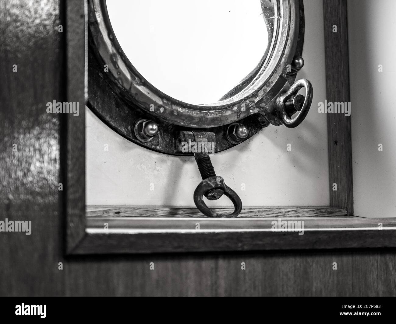 Closeup shot of a circular window of a ship with thick metal frames ...