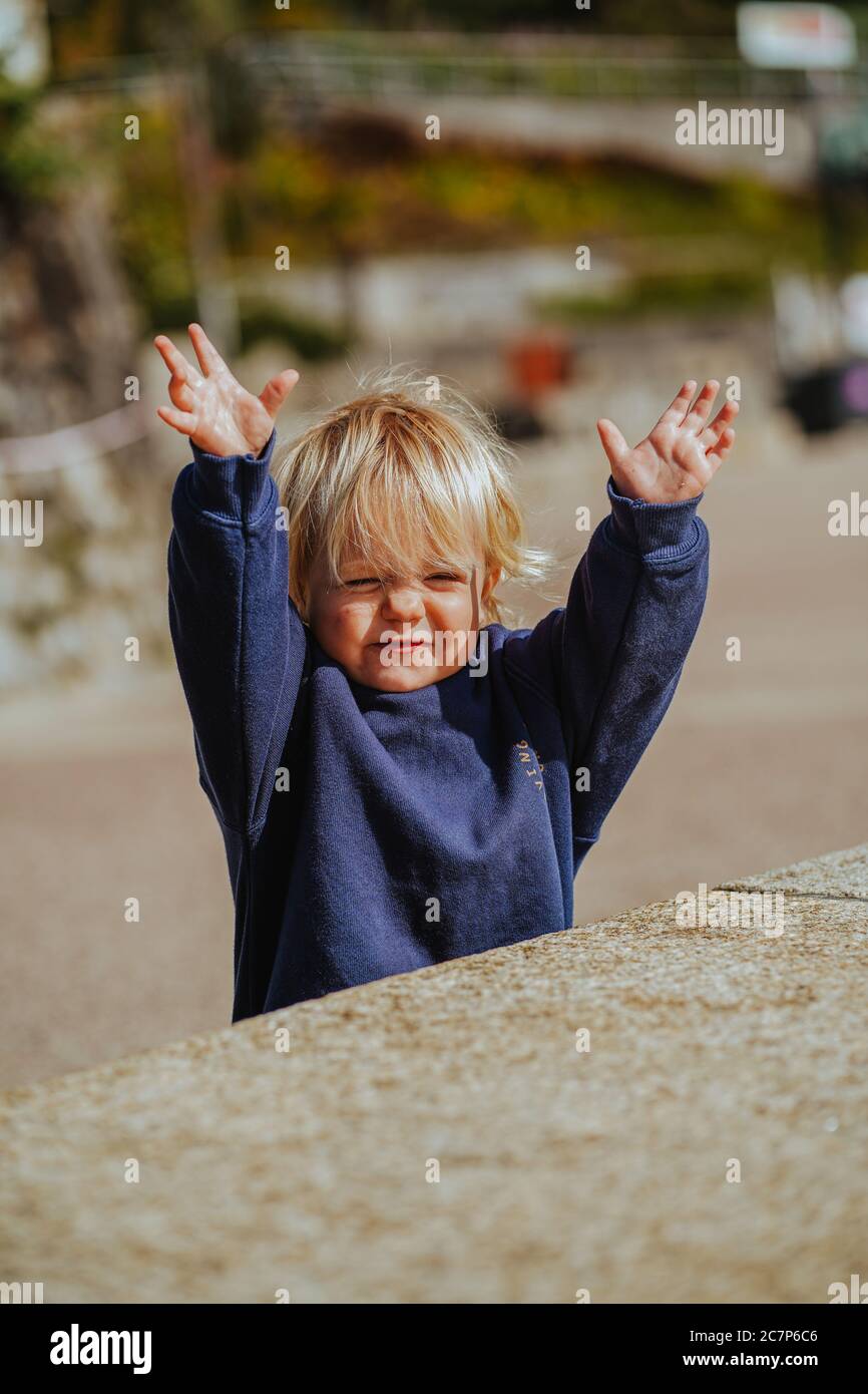 Blonde toddler reaching up to parent Stock Photo - Alamy