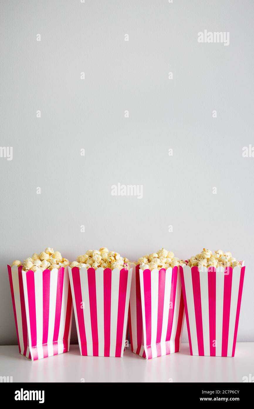popcorn in striped boxes and copy space over white wall background ...