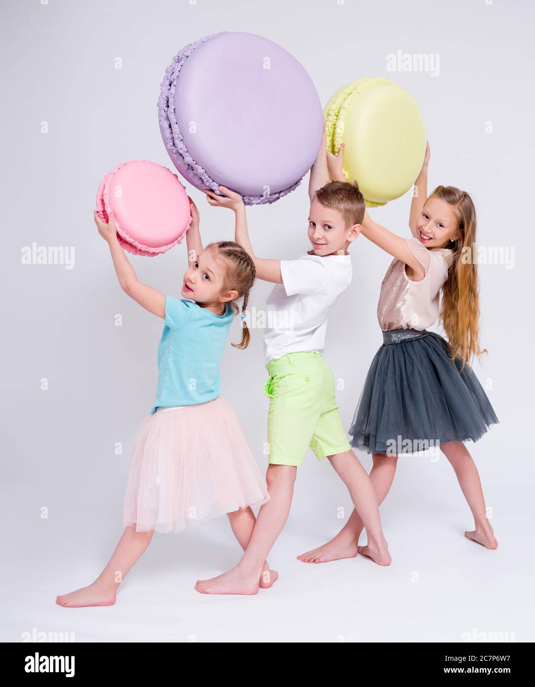 cute kids with big macaroons over white background Stock Photo - Alamy