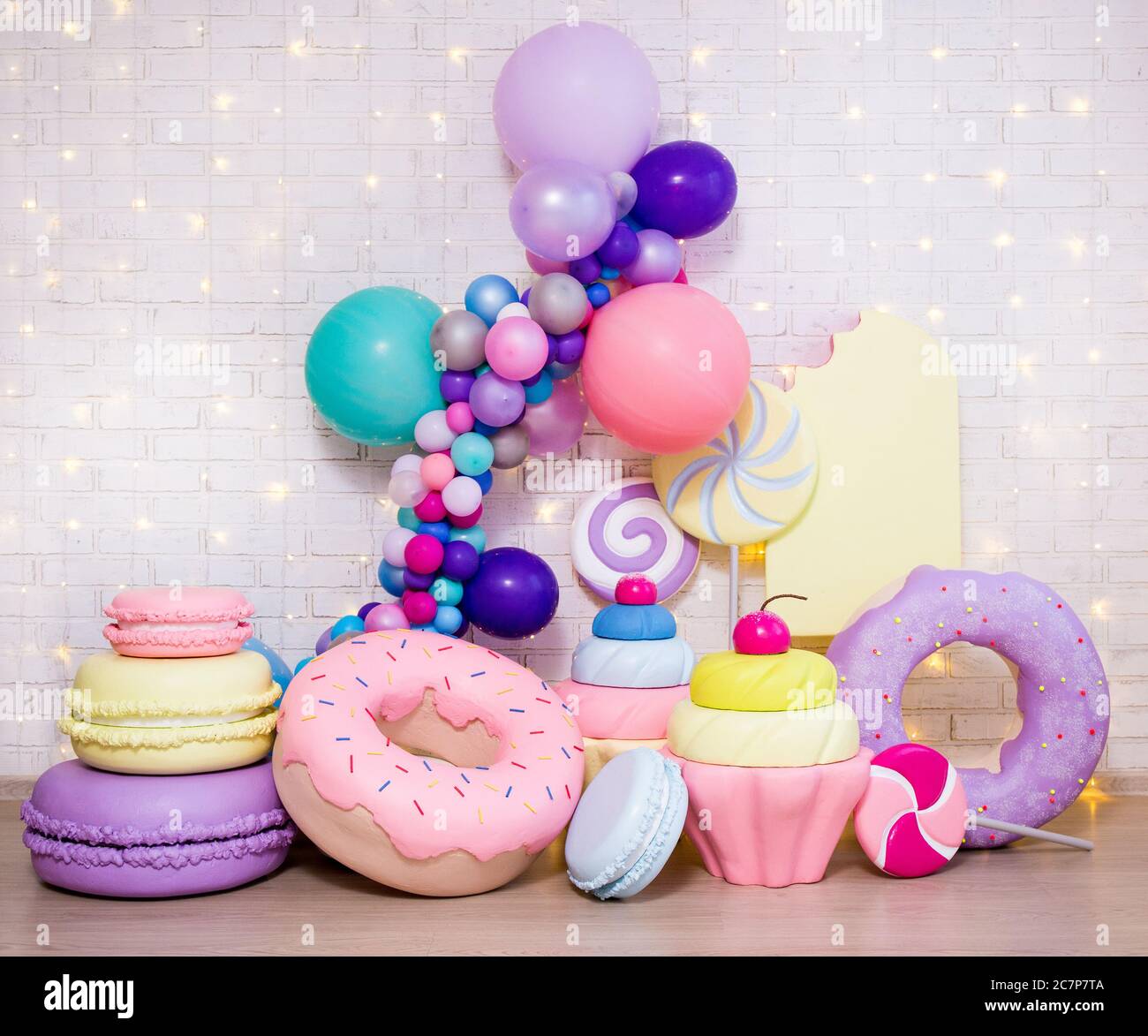 set of huge artificial sweets and pastry decorations over white brick ...
