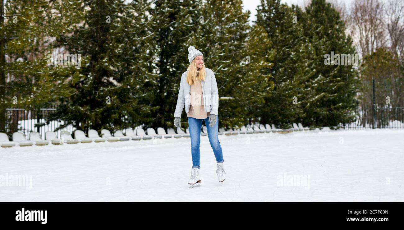 full length portrait of happy young beautiful woman ice skating at ...