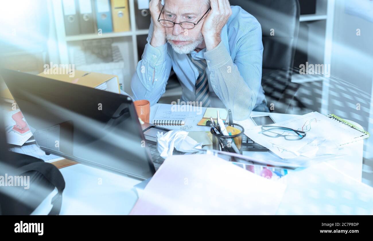 Overworked businessman sitting at a messy desk in office, light effect ...