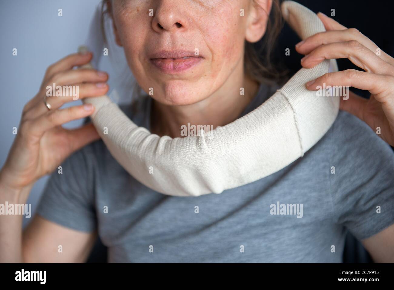 Mature woman in pain wearing a surgical collar on her neck ,working on ...