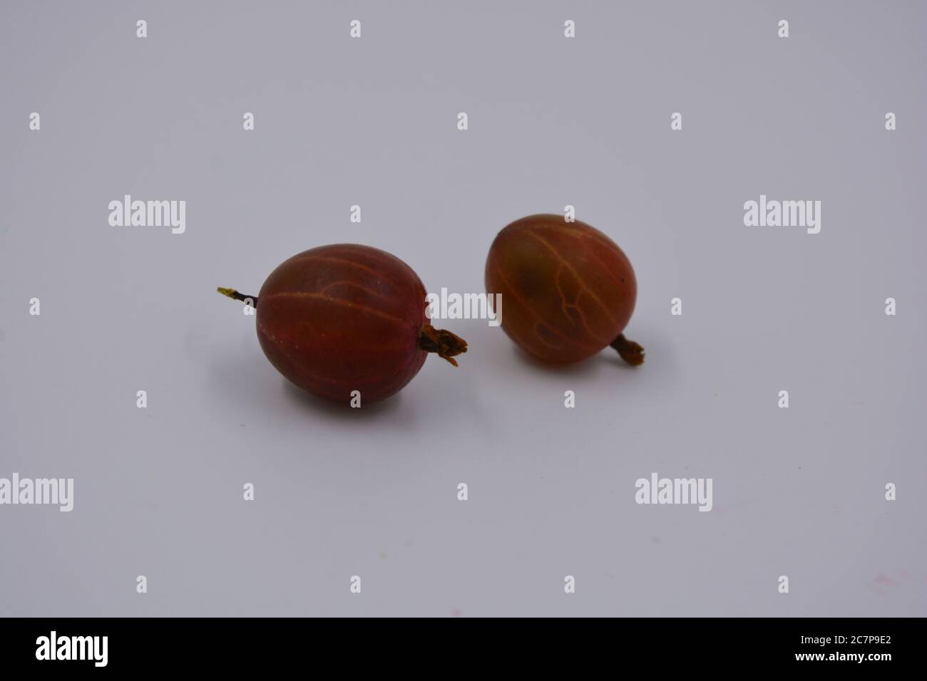 Large fruits of red juicy gooseberries located on a white matte ...