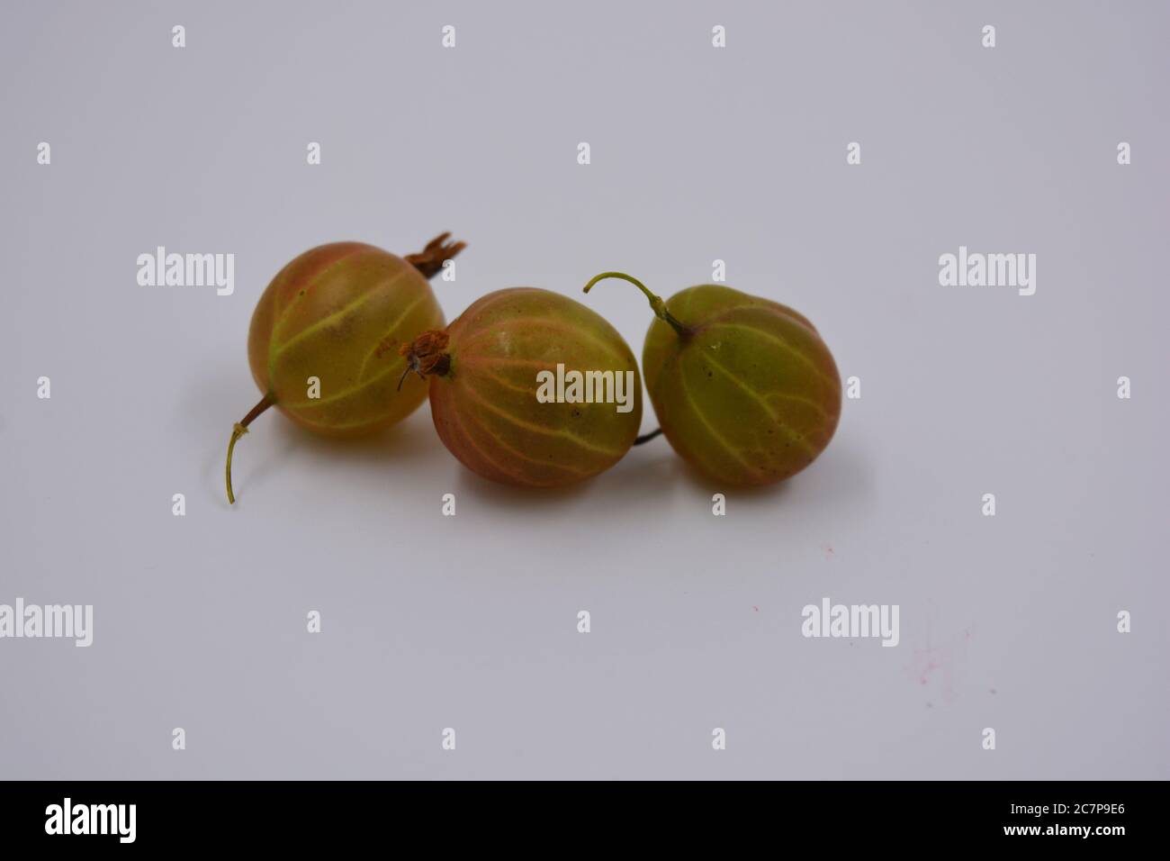 Large fruits of red juicy gooseberries located on a white matte ...