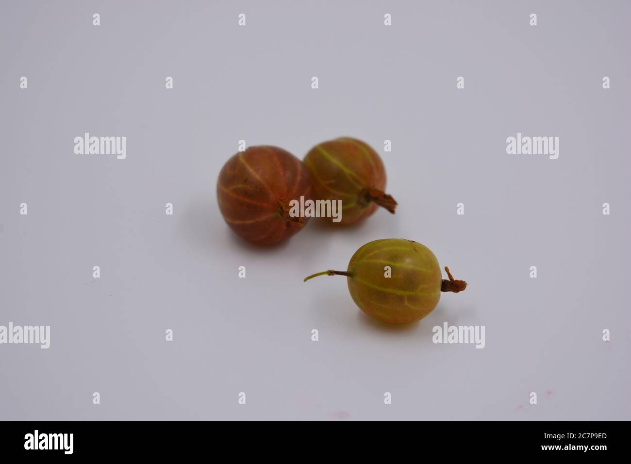Large fruits of red juicy gooseberries located on a white matte ...
