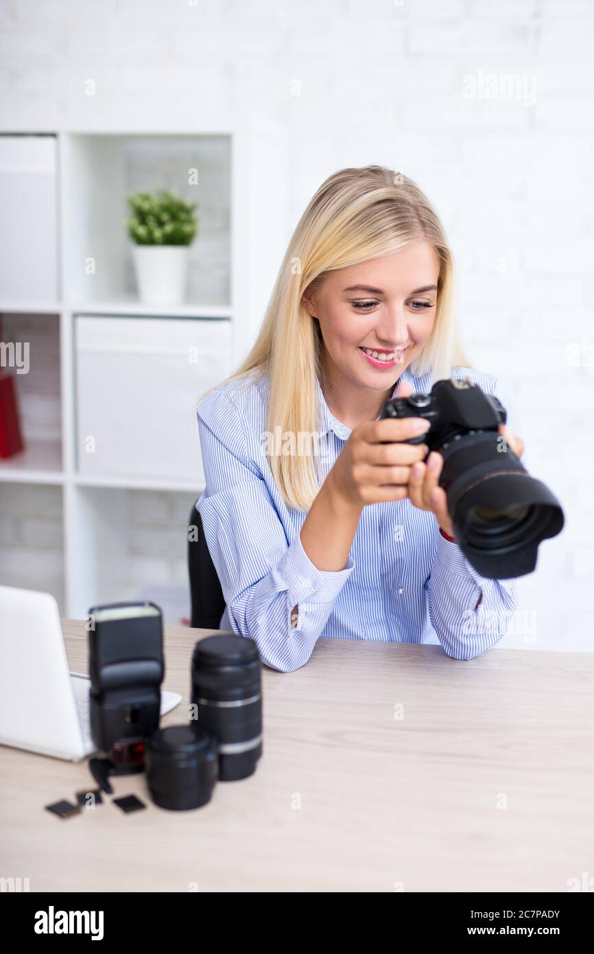 female photographer looking at display of digital camera in modern ...
