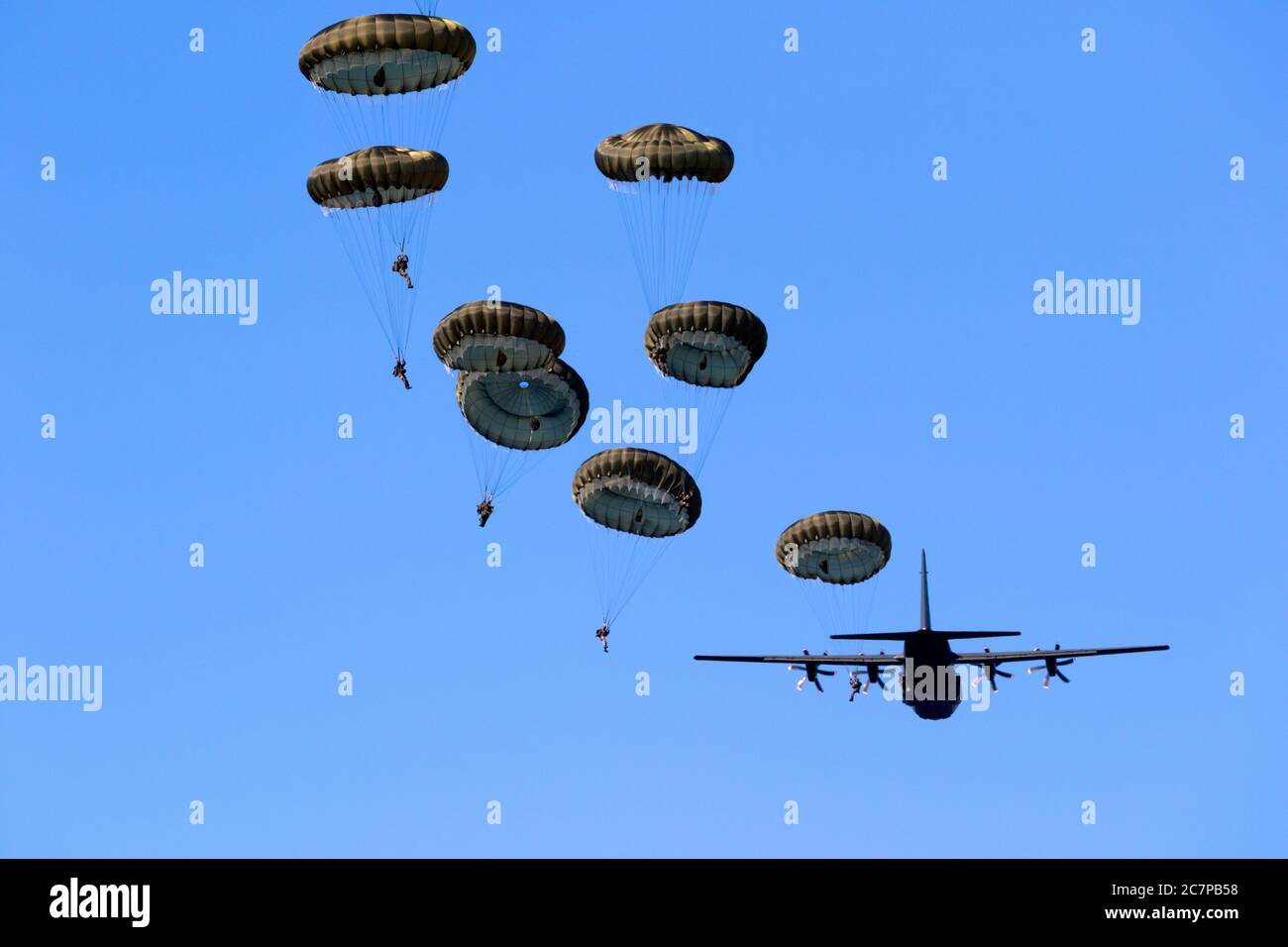 Military parachutist paratroopers jumping out of an air force airplane ...