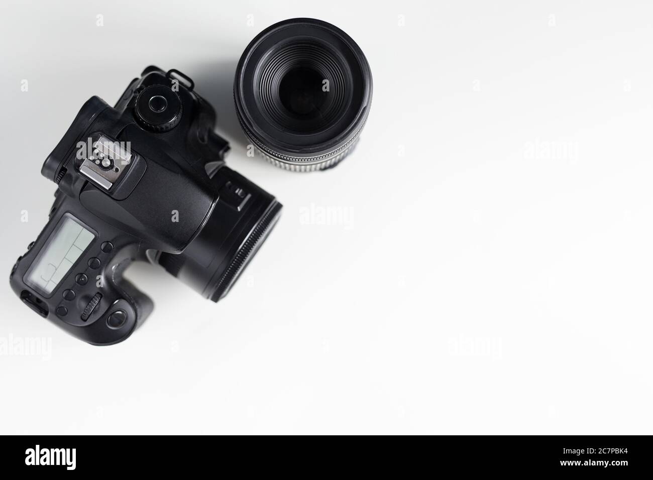 top view of modern photo camera and lens over white table background ...