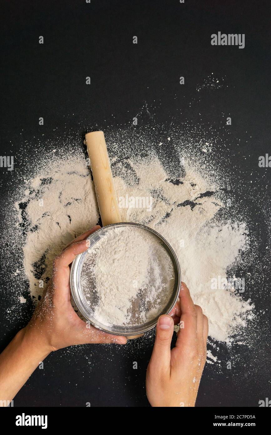 Males hands with flour sift flour with a sieve for making dough ...