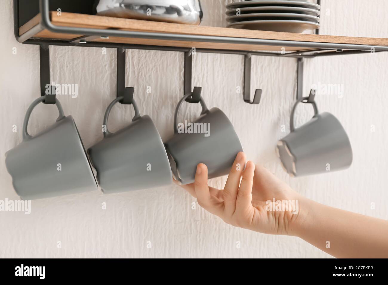 Woman hanging cup on shelf in kitchen Stock Photo - Alamy