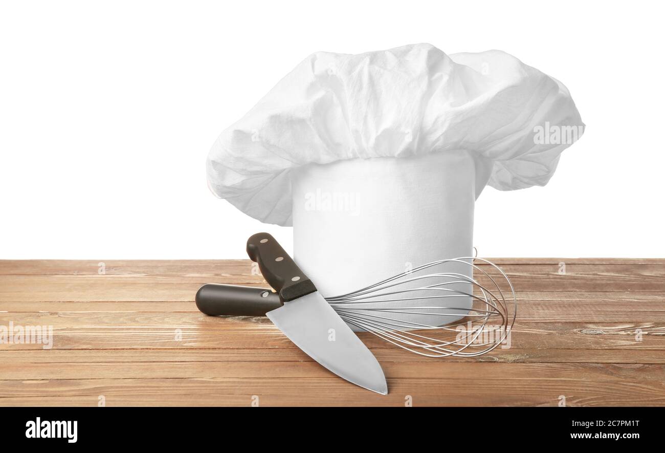 Chef's hat and utensils on table against white background Stock Photo ...