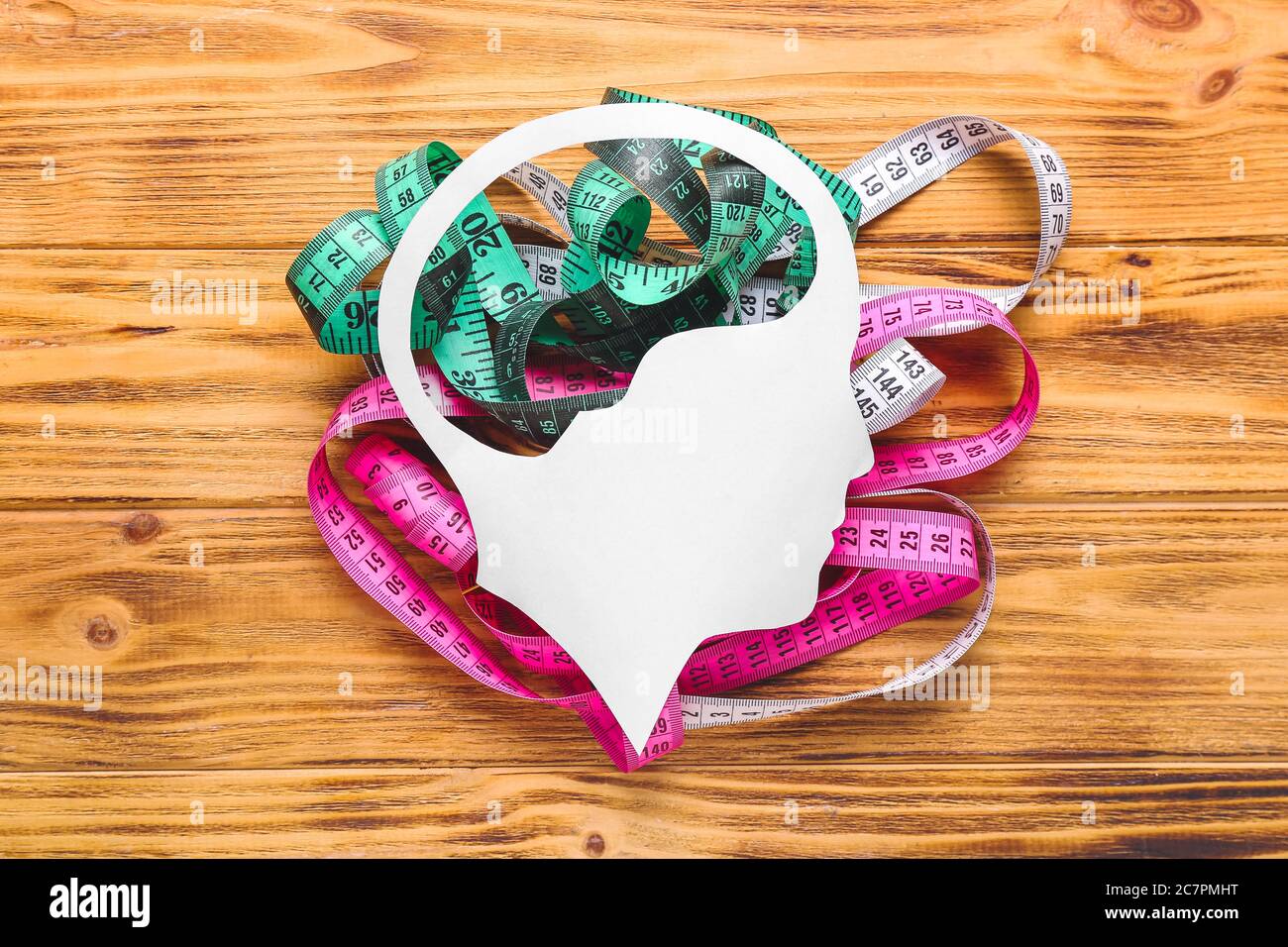 Paper figure of human head with measuring tapes on wooden background ...