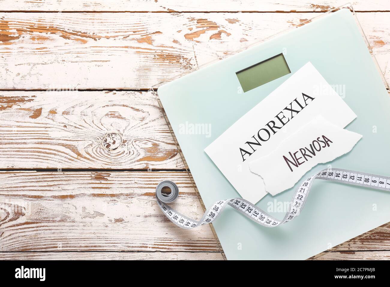 Scales with measuring tape and text ANOREXIA NERVOSA on white wooden ...