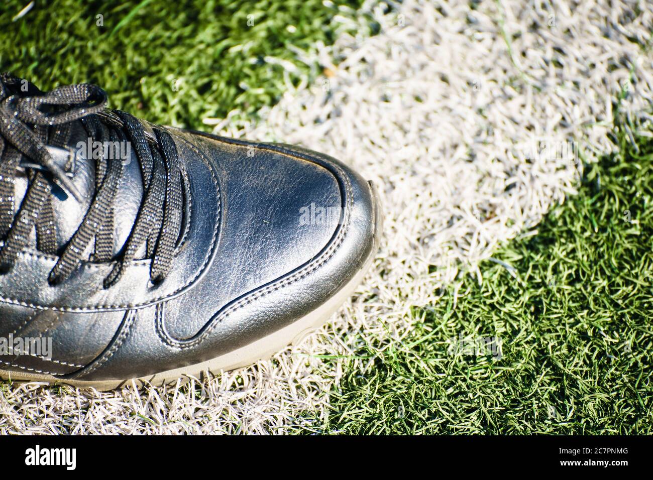 Top view shot foot standing on the white line on green soccer field ...