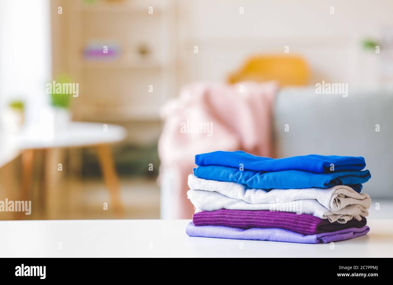 Stack of clean clothes on table in room Stock Photo - Alamy