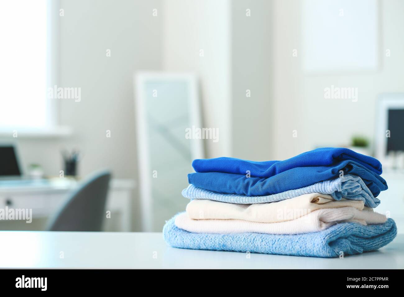 Stack of clean clothes on table in room Stock Photo - Alamy
