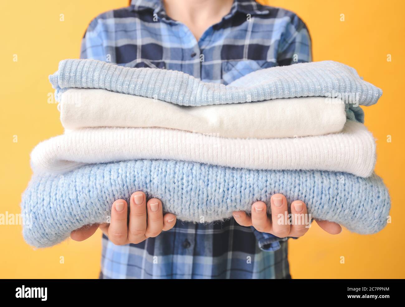 Woman with stack of clean clothes on color background, closeup Stock ...