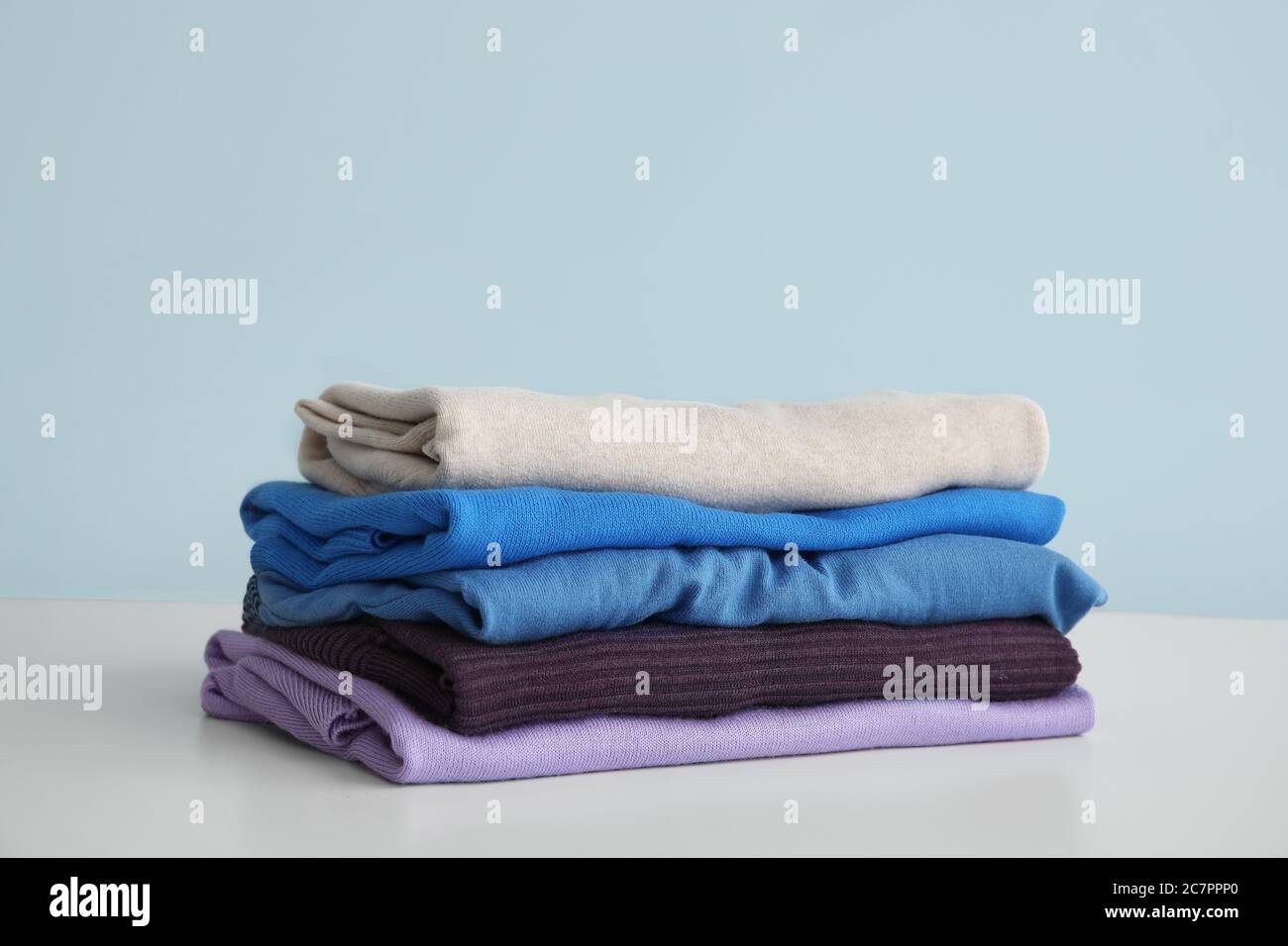 Stack of clean clothes on table against color background Stock Photo ...