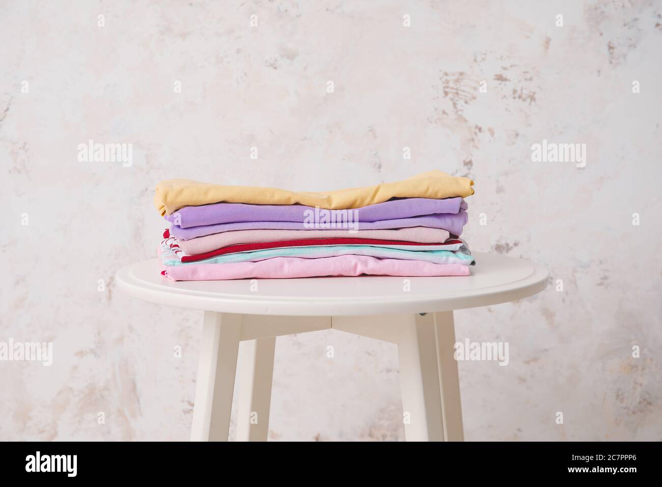 Stack of clean clothes on table against light background Stock Photo ...