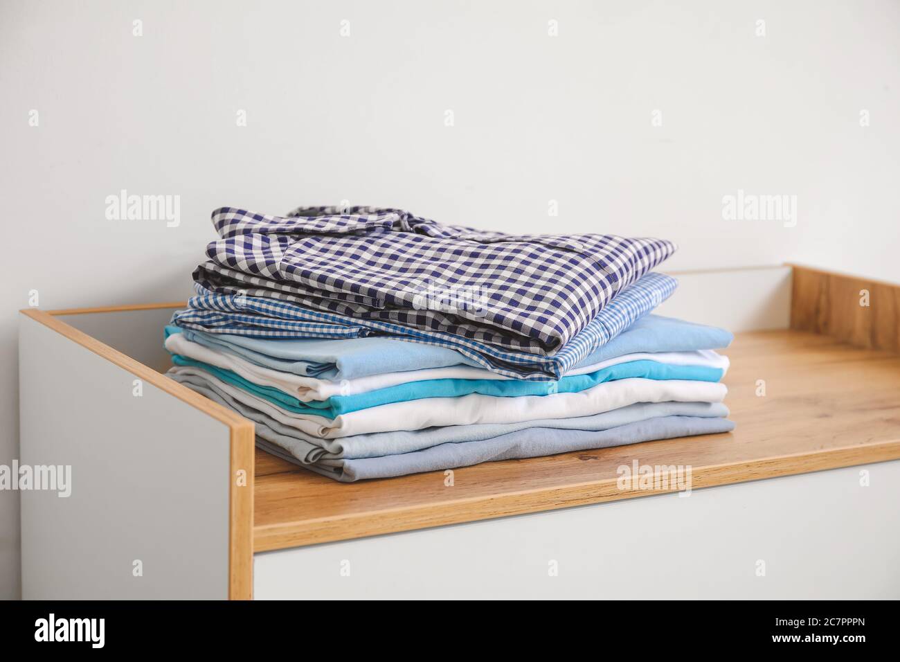 Stack of clean clothes on chest of drawers in room Stock Photo - Alamy