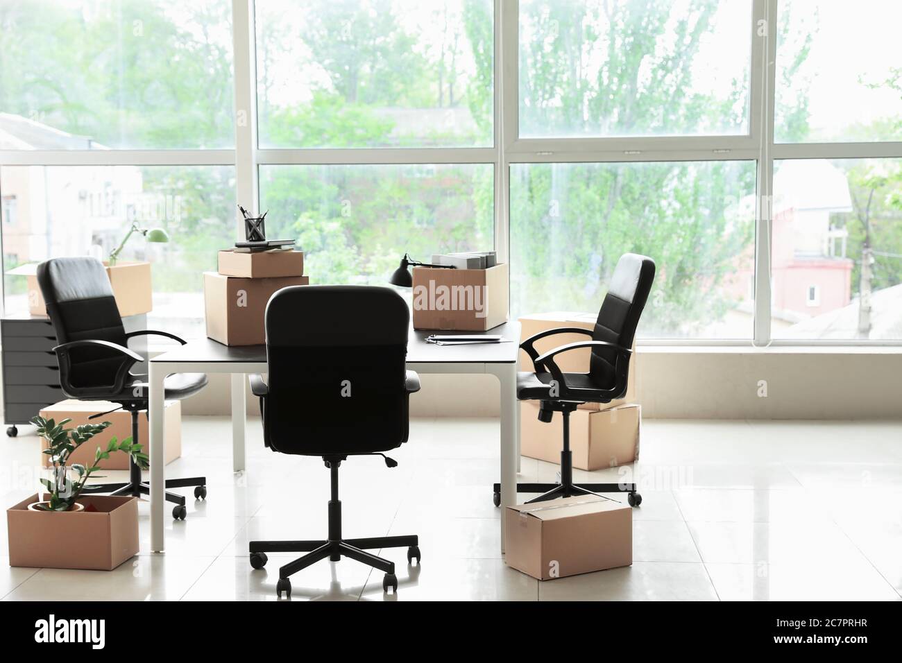Cardboard boxes with belongings and furniture in new office on moving ...