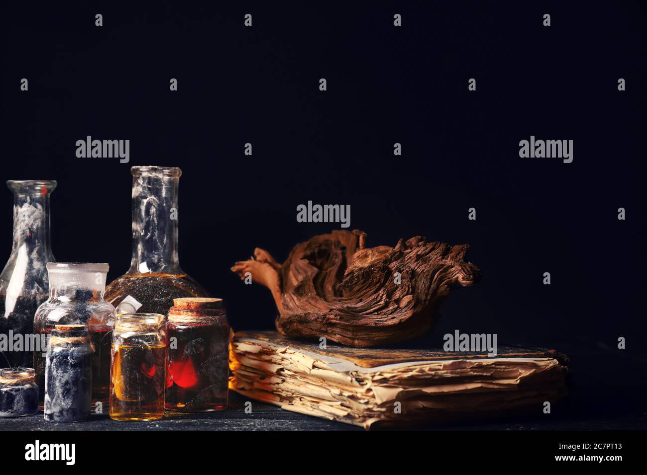 Potions and old book on alchemist's table Stock Photo - Alamy