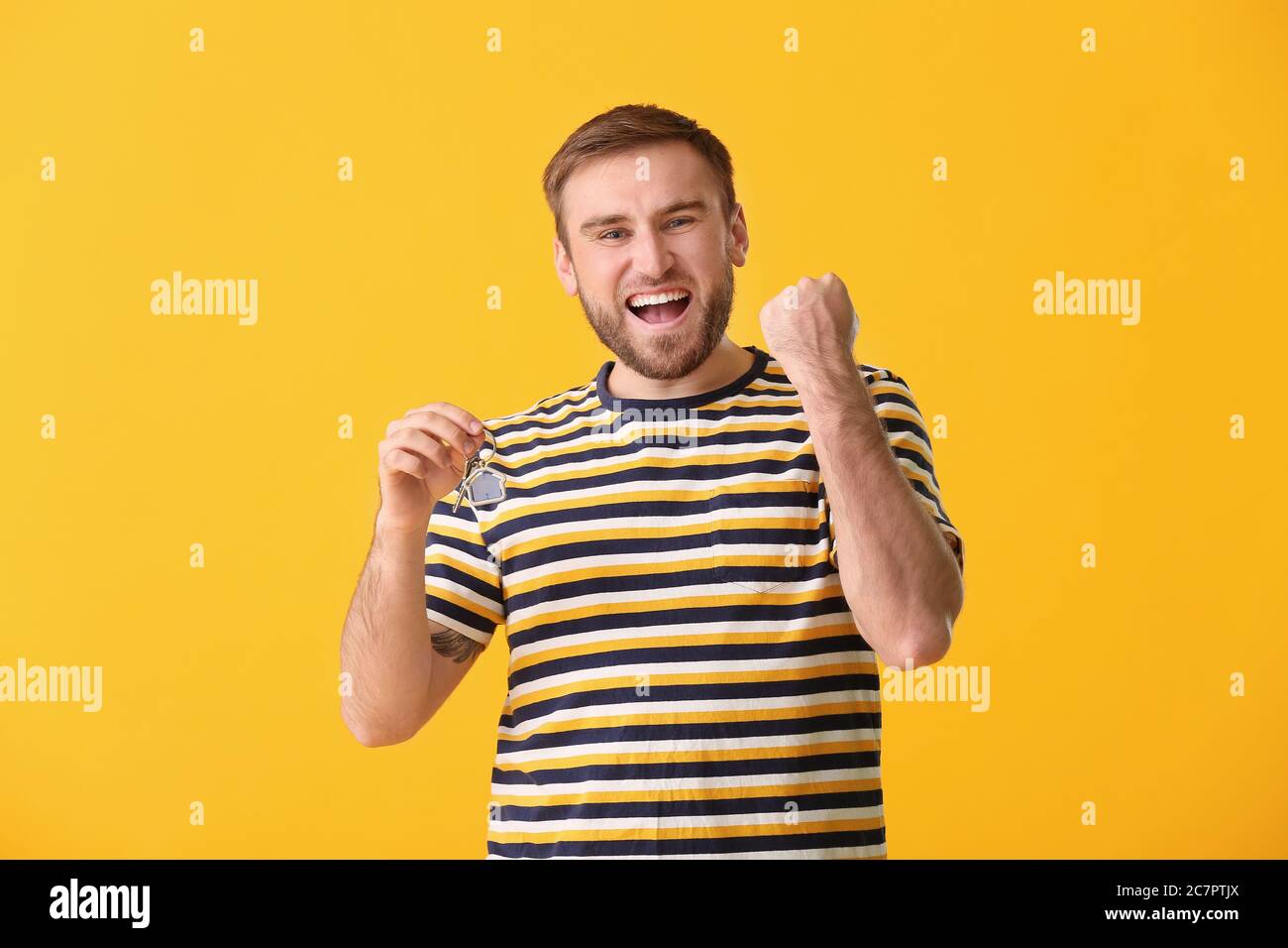 Happy young man with key on color background Stock Photo - Alamy