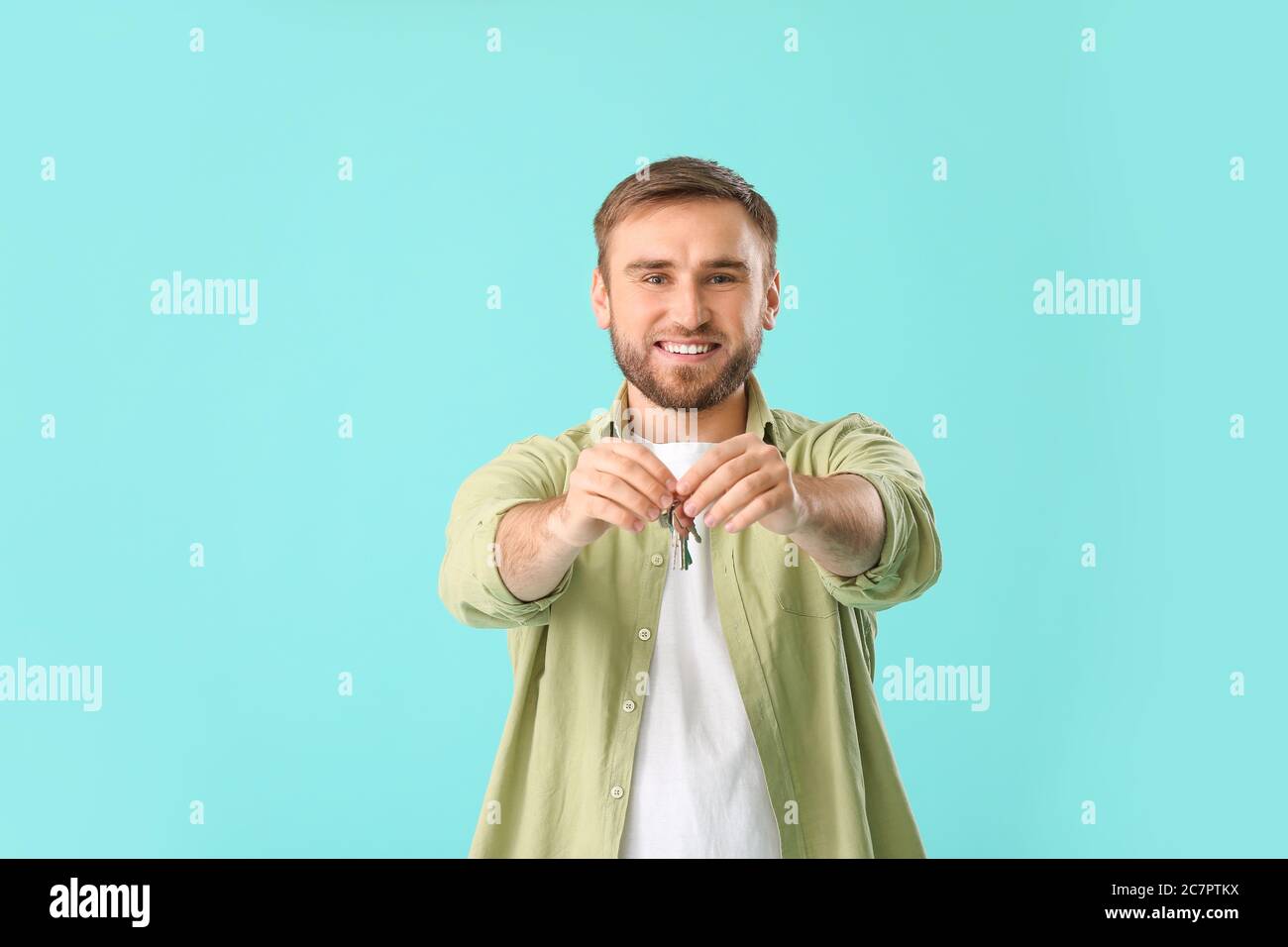 Happy young man with key on color background Stock Photo - Alamy