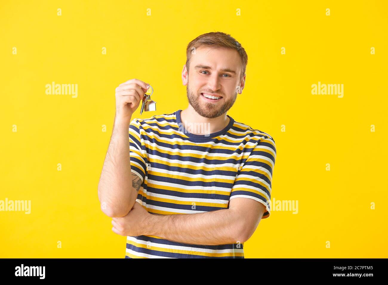 Happy young man with key on color background Stock Photo - Alamy