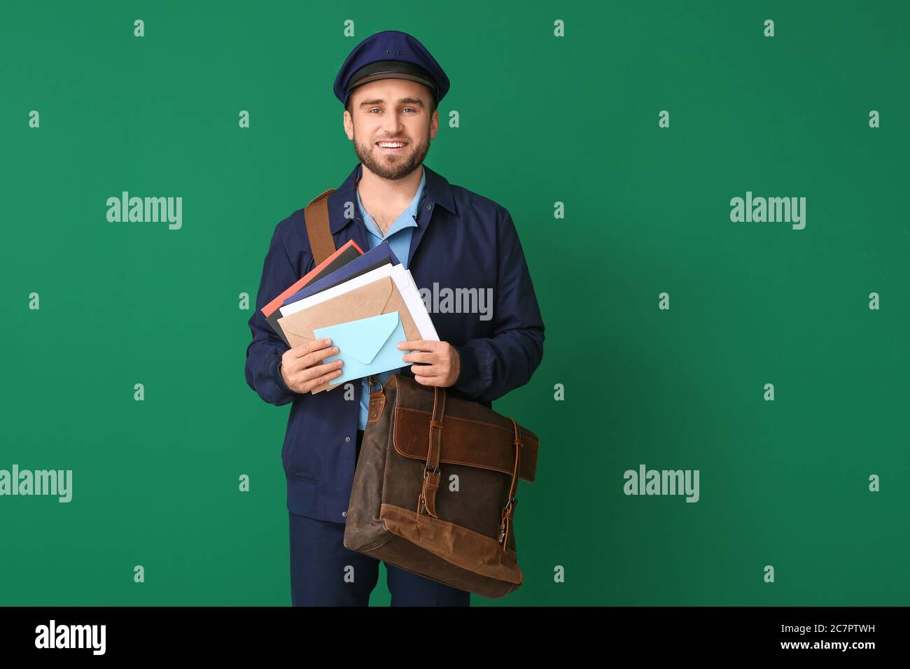 Handsome young postman on color background Stock Photo - Alamy