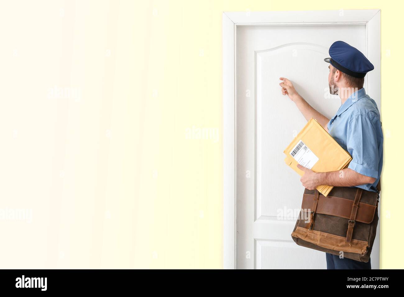 Handsome young postman knocking at the door Stock Photo - Alamy