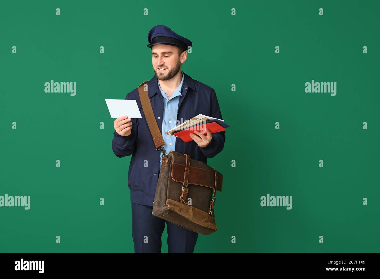 Handsome young postman on color background Stock Photo - Alamy