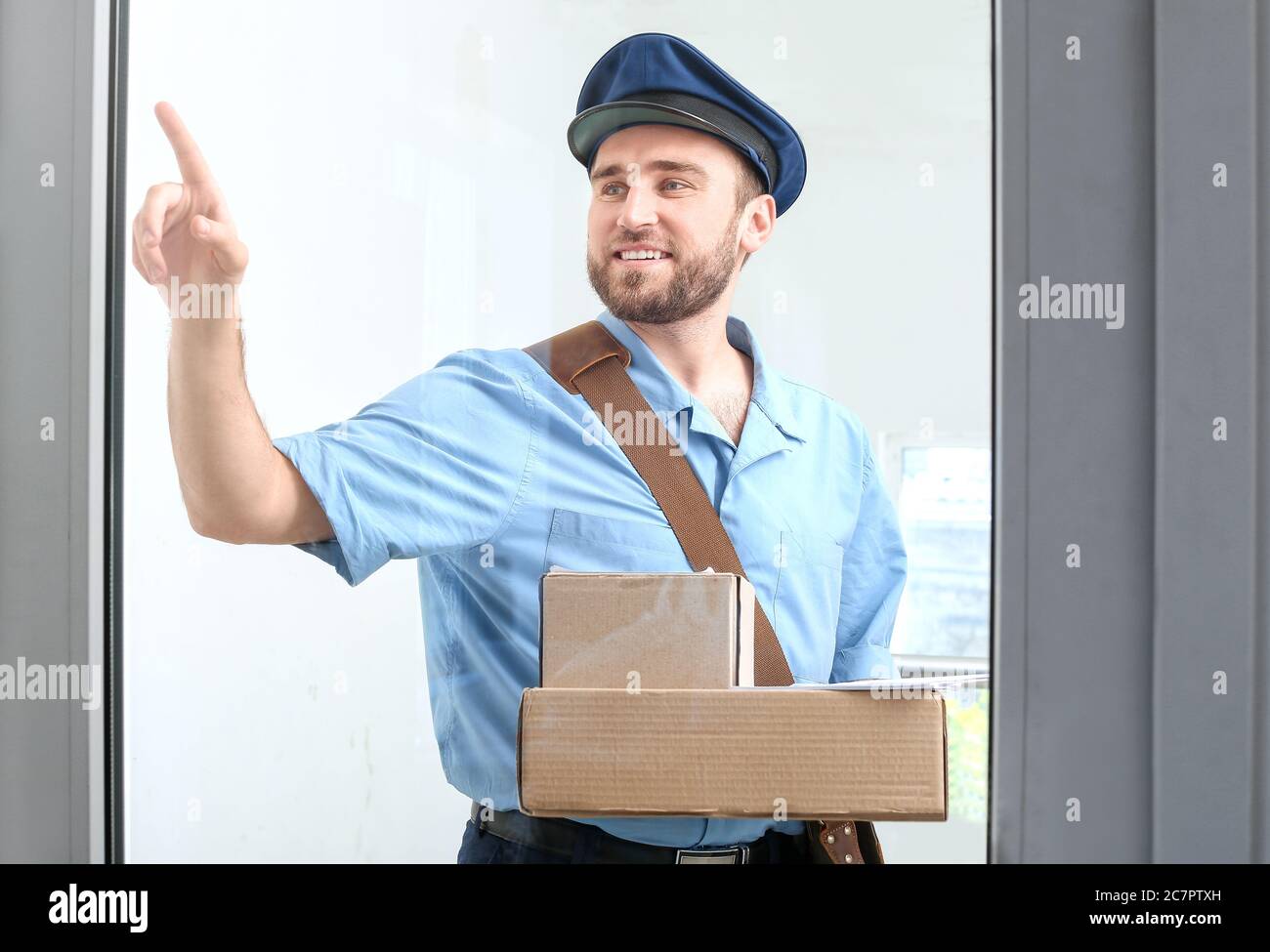 Handsome young postman ringing the door bell Stock Photo - Alamy