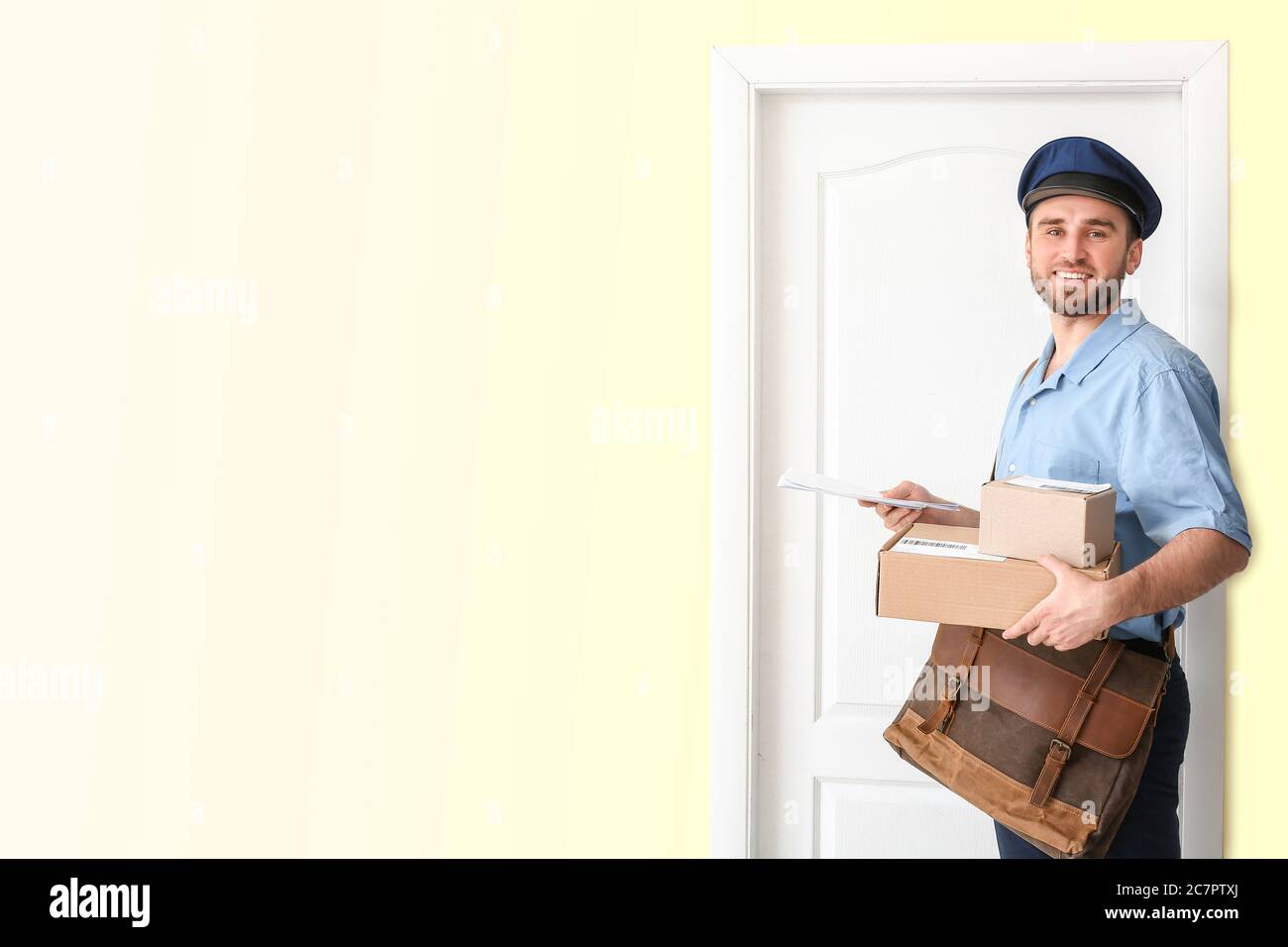 Handsome young postman near door Stock Photo - Alamy